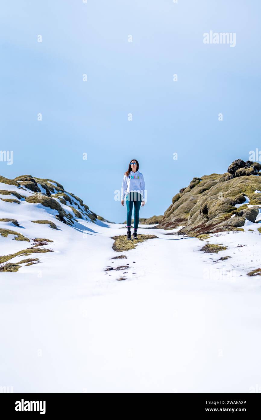 A female figure stands atop a picturesque snow-capped mountain, with a ...