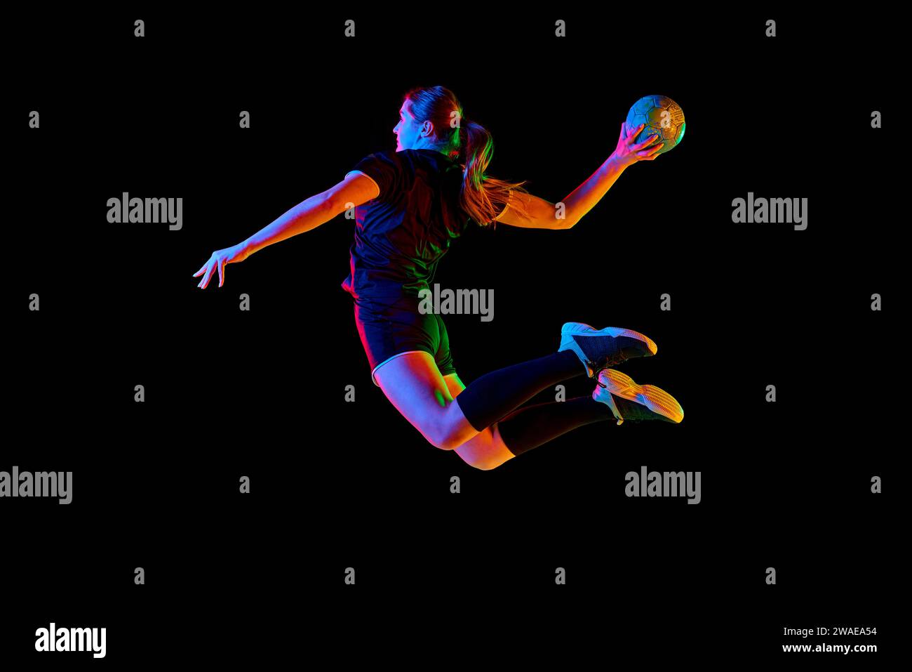 Young female handball athlete practicing throws and receptions against ...