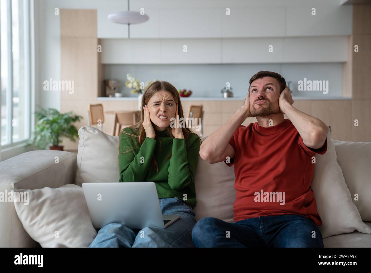 Annoyed family couple closed ears listening terrible noise from ...