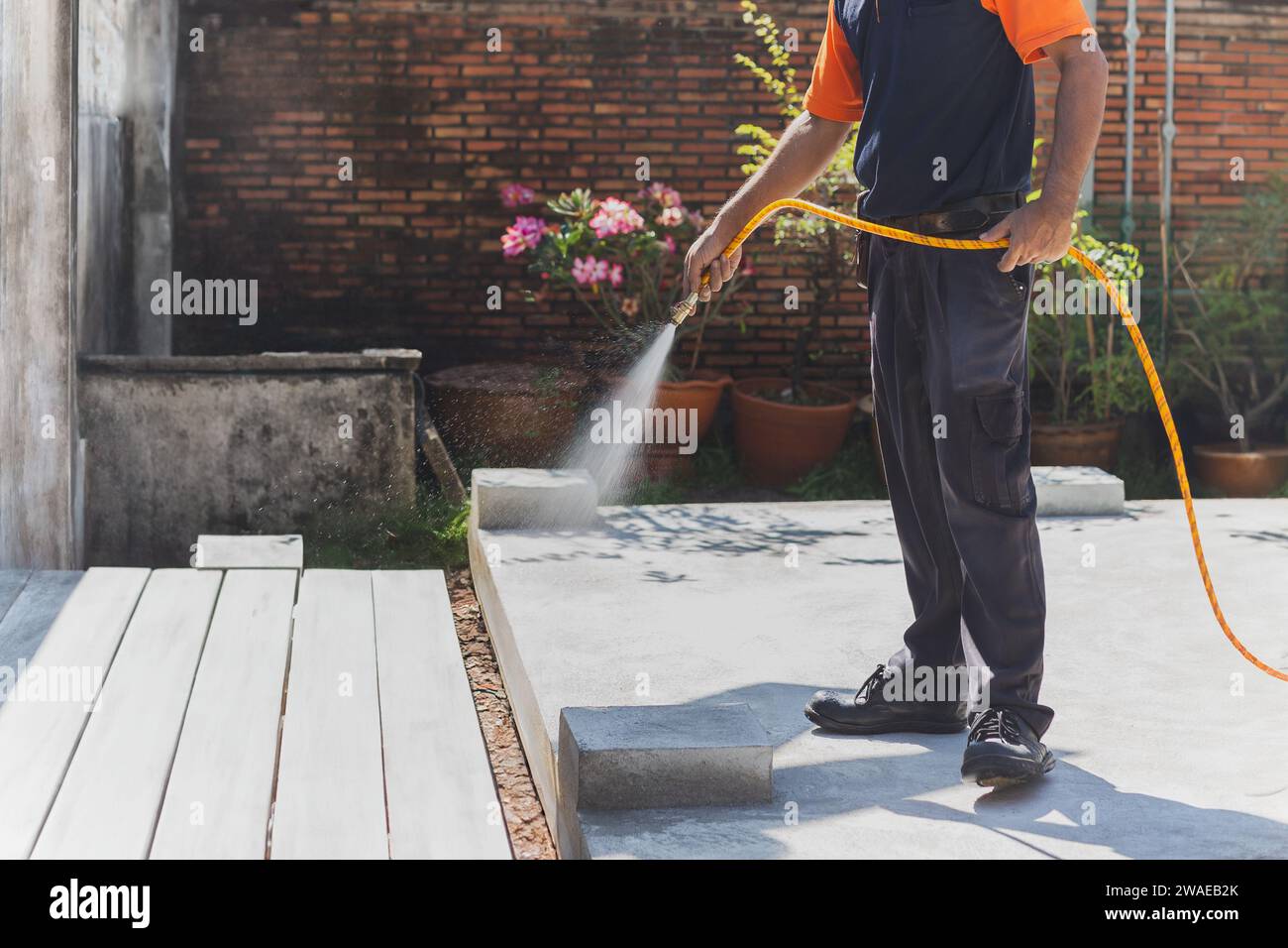 Termite controler spraying cemicals outside the house into the soil and ...