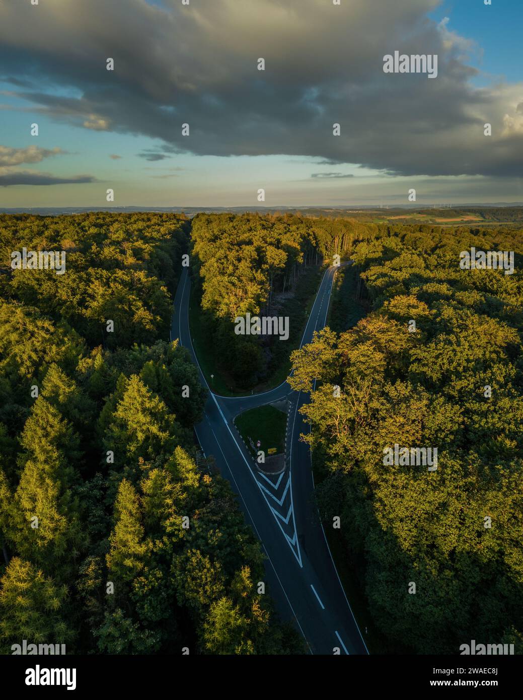 An aerial view of a winding road cutting through lush green forests ...