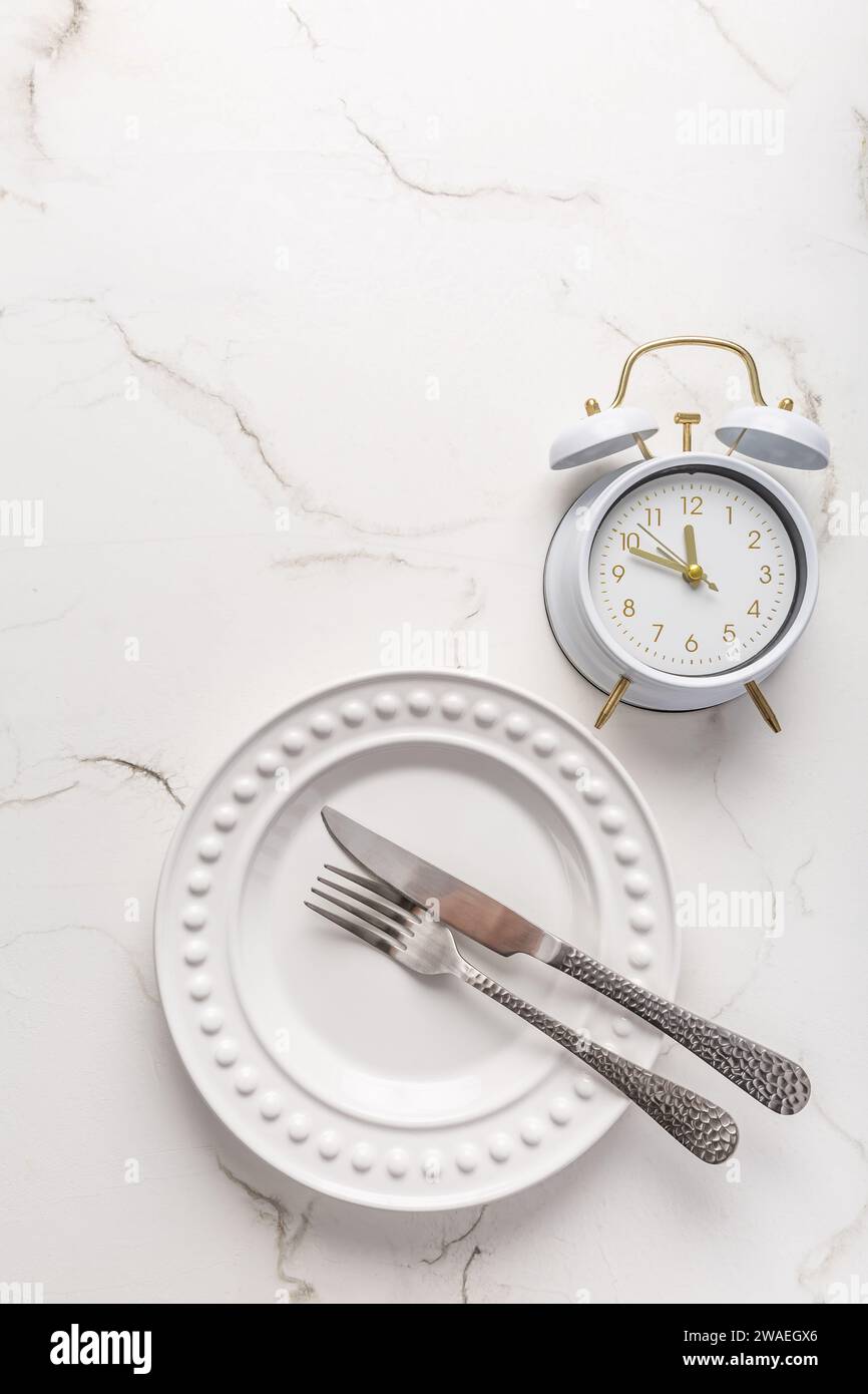 Concept of intermittent fasting, empty plate with clock on white Stock ...