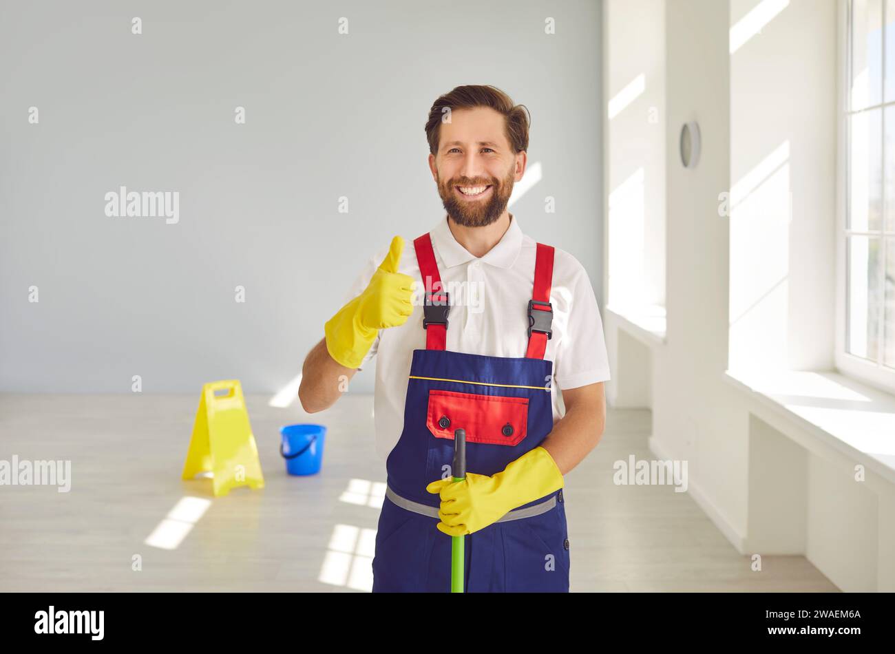 Smiling Janitor Poses with Mop Giving a Thumbs Up Stock Photo - Alamy