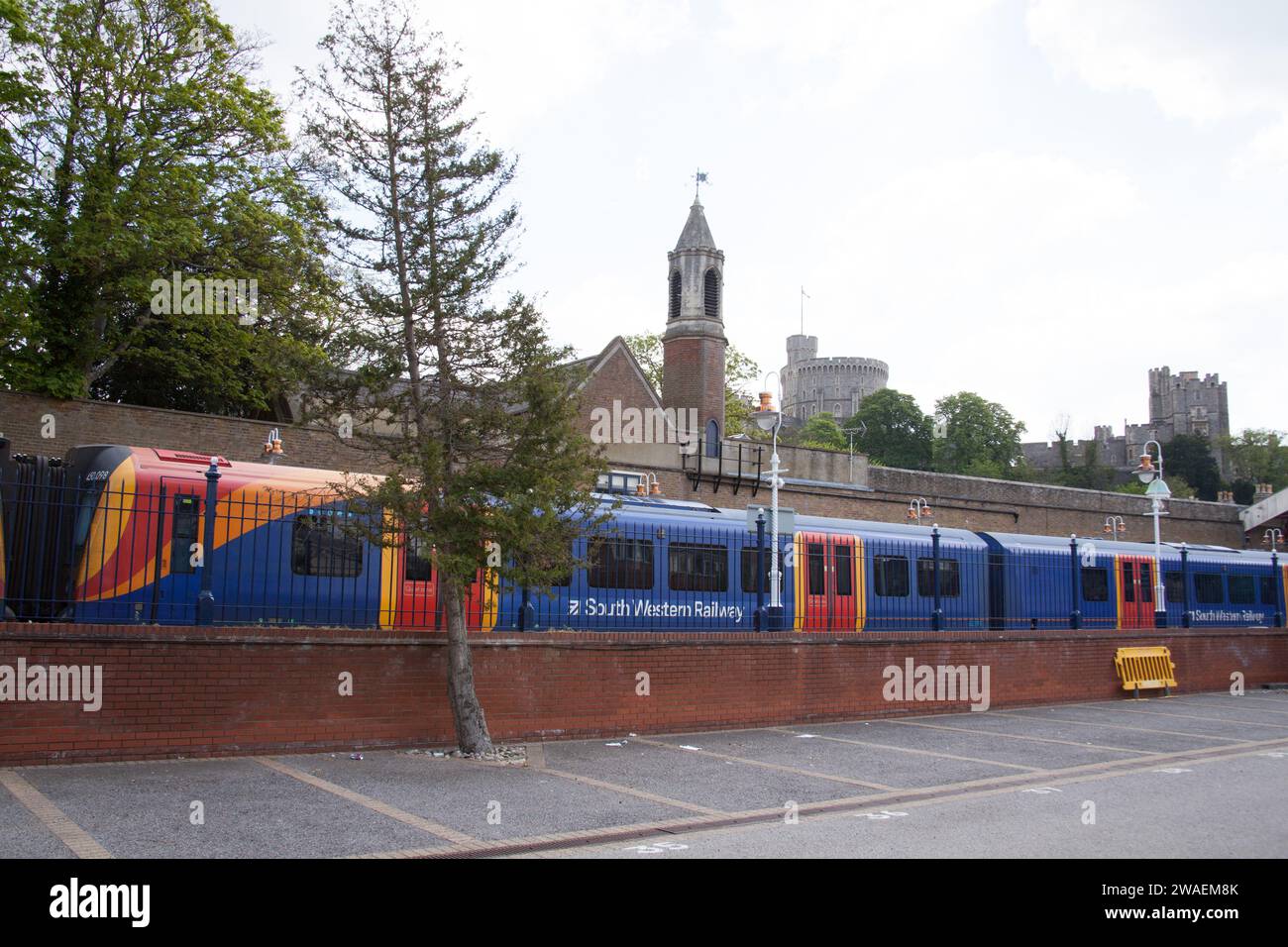 A train pulls up at the station in Windsor with Windsor Castle behind ...