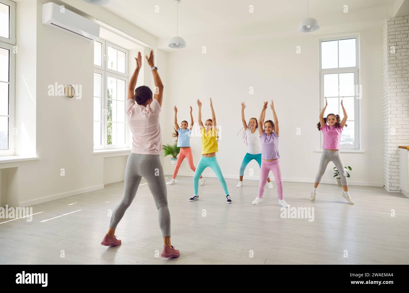 Group of children with help of trainer practice energetic dance moves ...