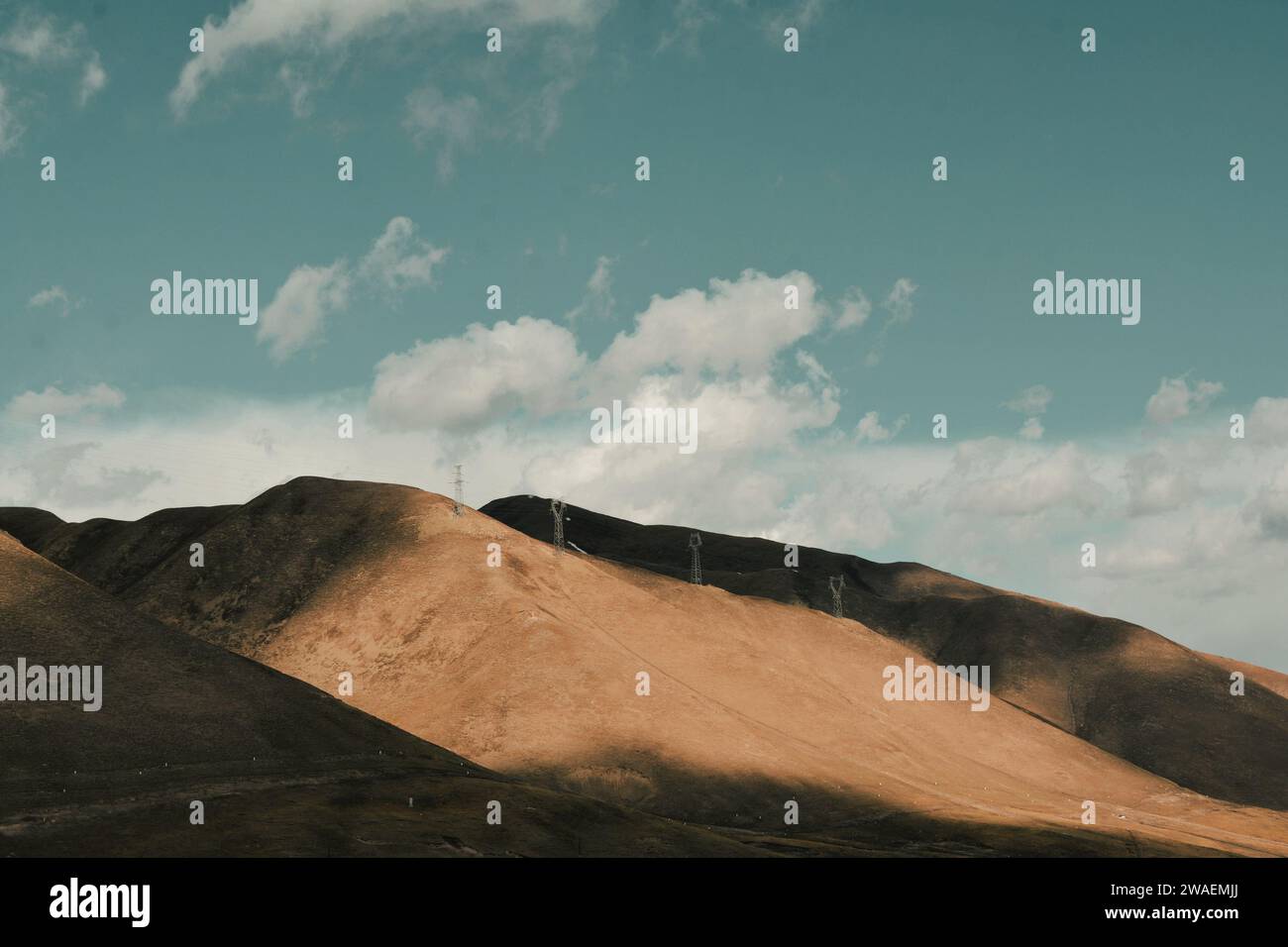 An aerial view of a stretch of countryside featuring two rolling hills ...