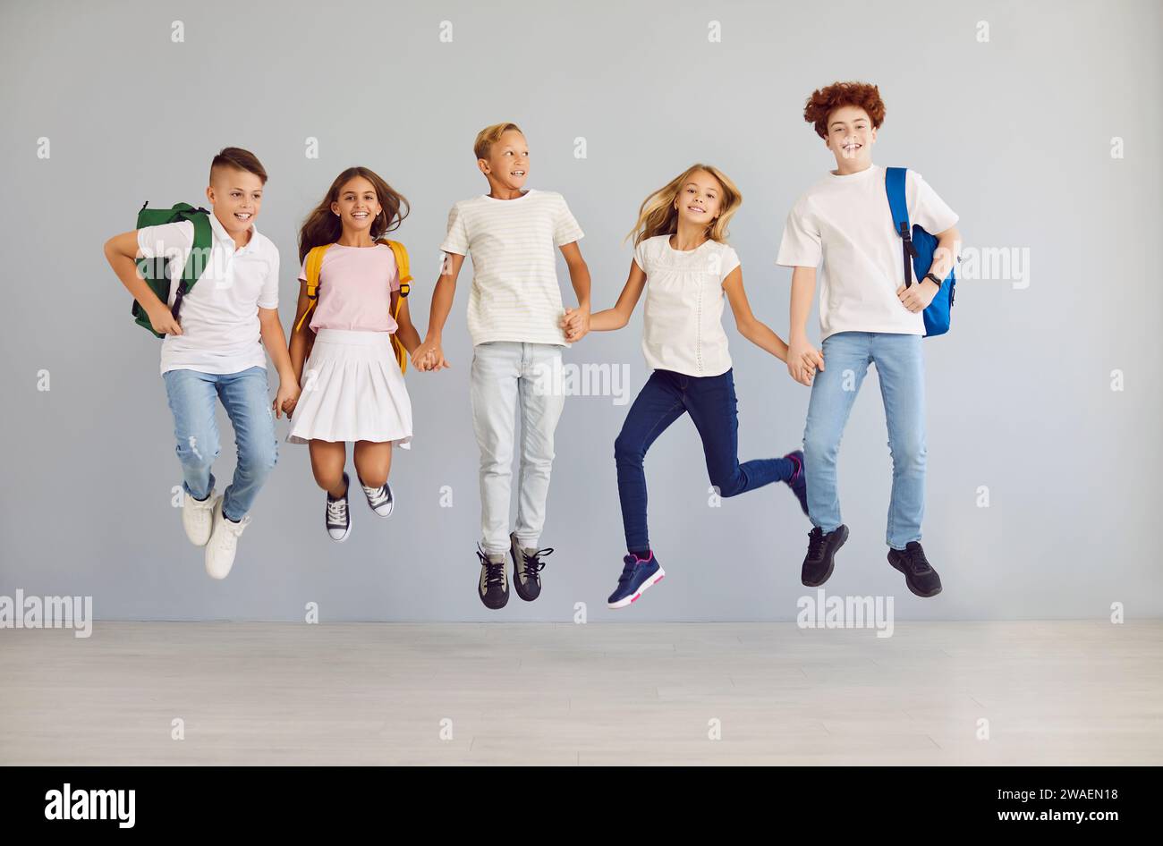 Happy school children looking cheerful at camera, holding hands and ...