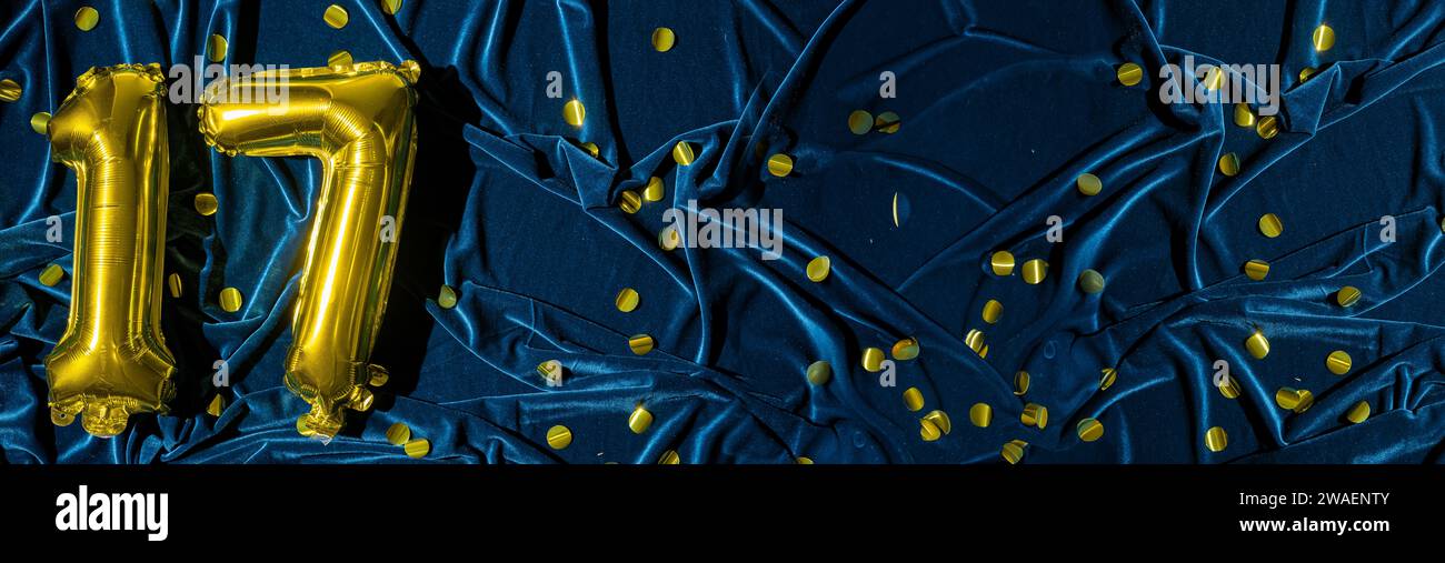 number seventeen, gold foil balloon number on a blue velvet background ...