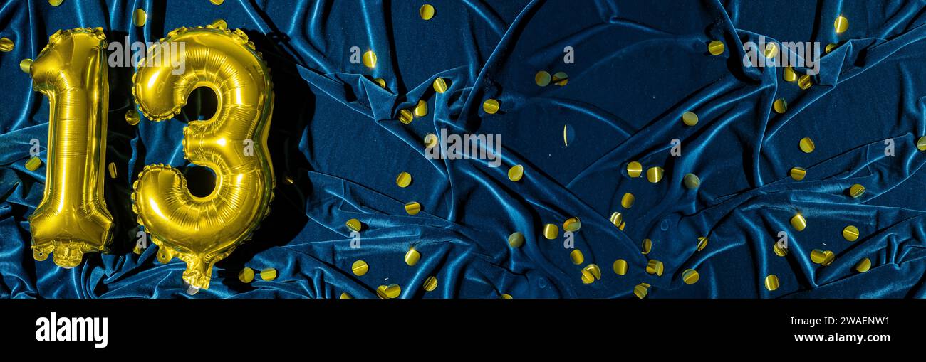 number thirteen, gold foil balloon number on a blue velvet background ...