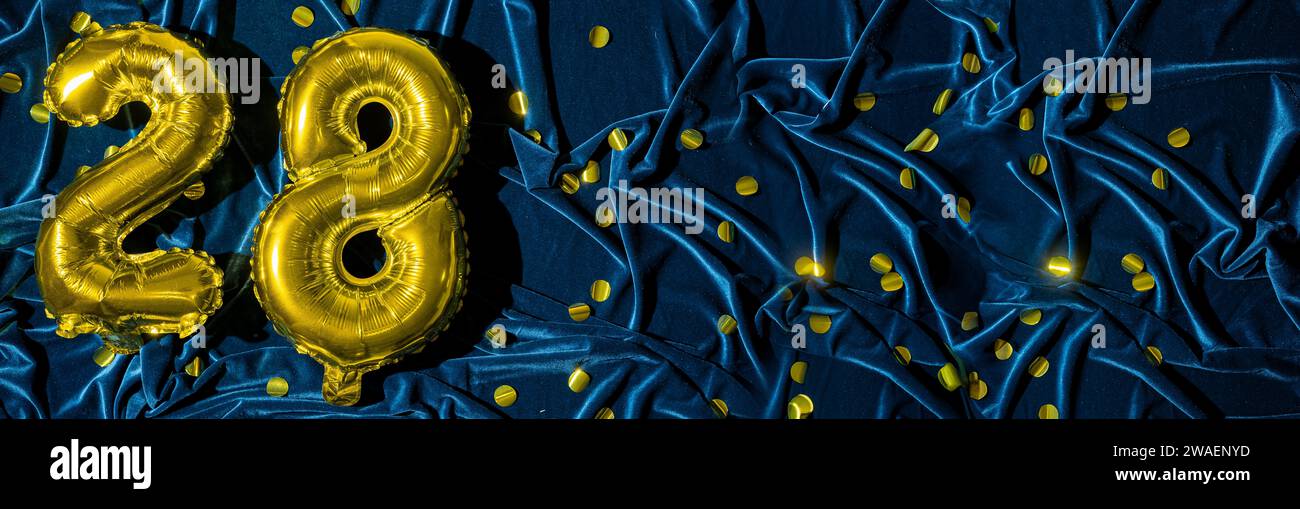 number twenty eight, gold foil balloon number on blue velvet background ...