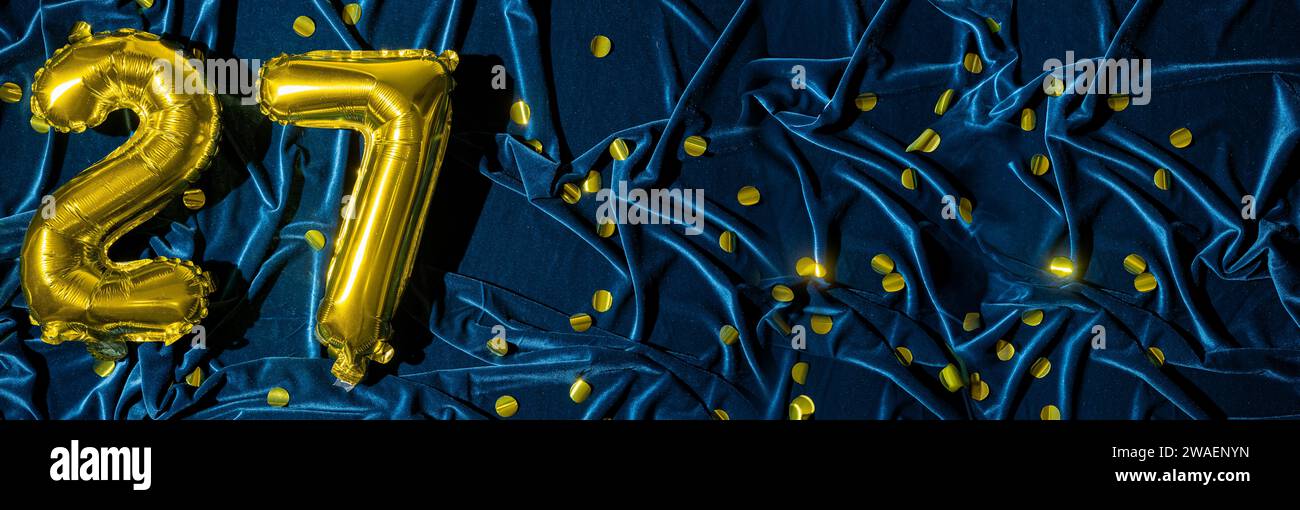 number twenty seven, gold foil balloon number on blue velvet background ...