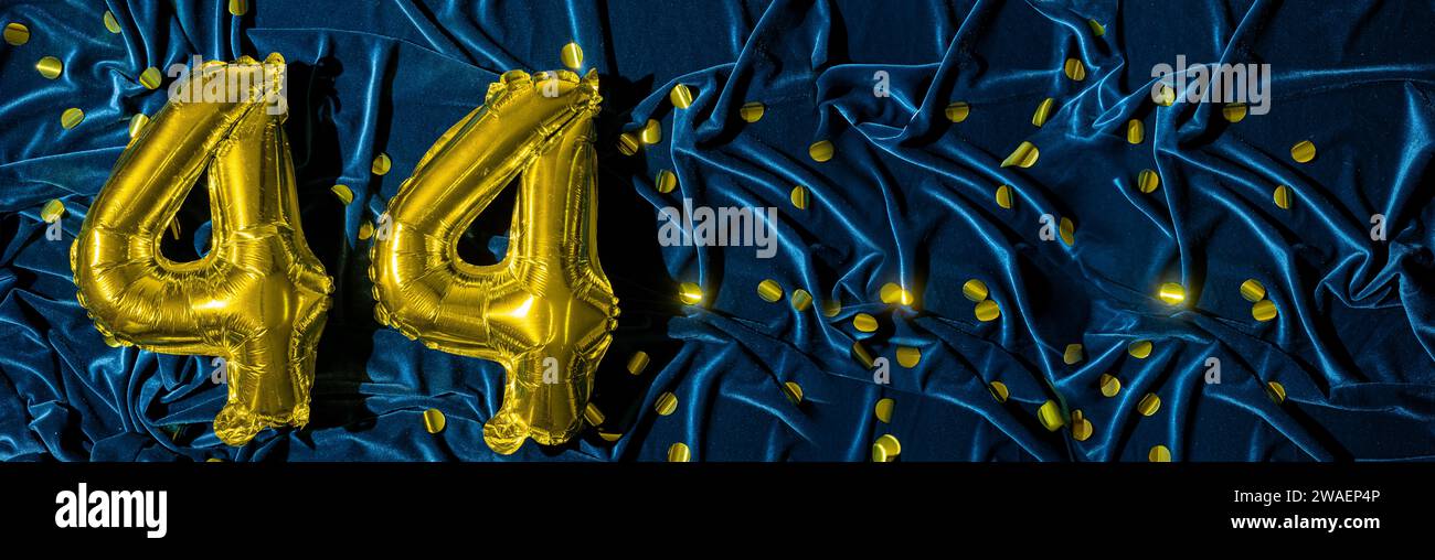 number forty four, gold foil balloon number on a blue velvet background ...