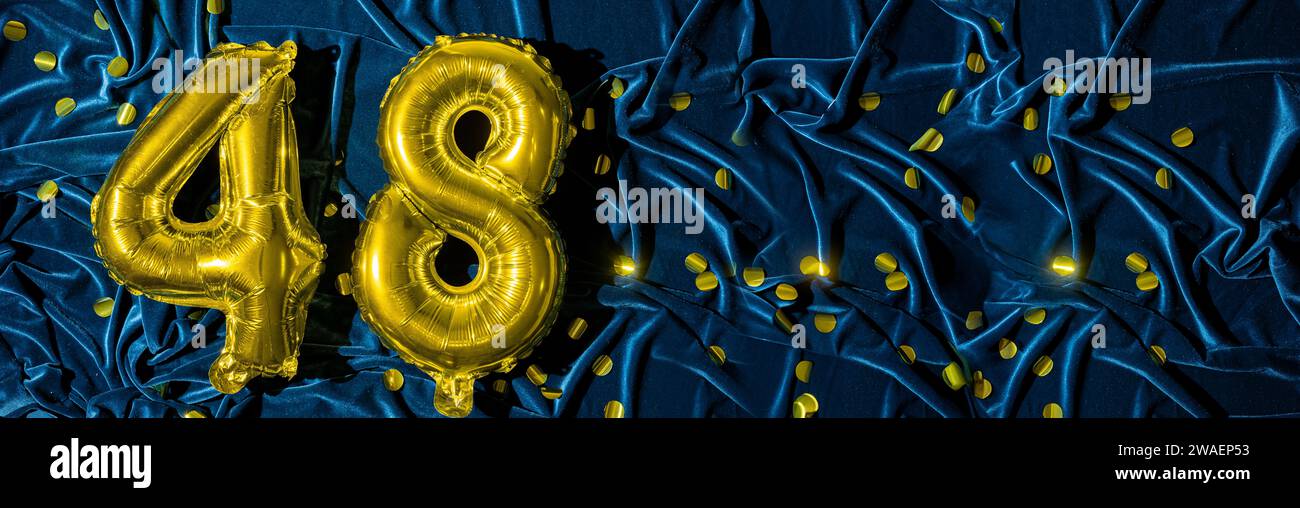 number forty eight, gold foil balloon number on a blue velvet ...