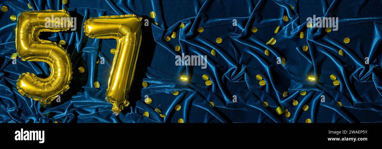 Gold foil balloon number number 57 on a background of blue velvet ...