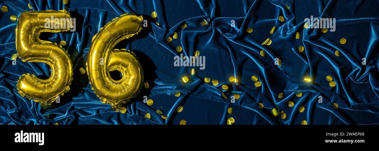 Gold foil balloon number number 56 on a background of blue velvet ...