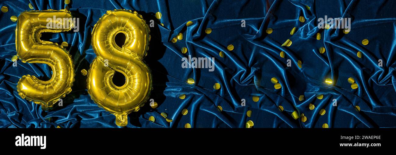 Gold foil balloon number number 58 on a background of blue velvet ...
