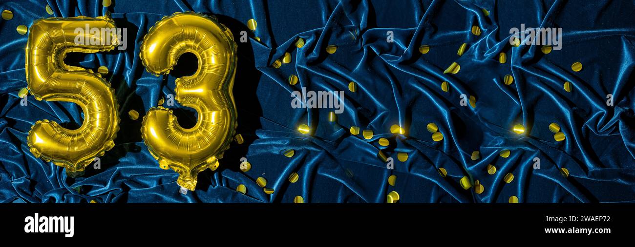 Gold foil balloon number number 53 on a background of blue velvet ...