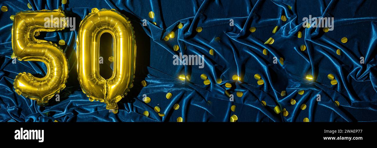 number fifty, gold foil balloon number on a blue velvet background with ...