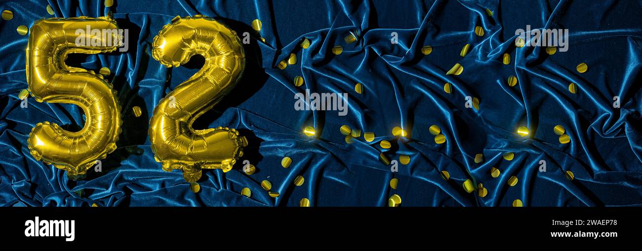 Gold foil balloon number number 52 on a background of blue velvet ...