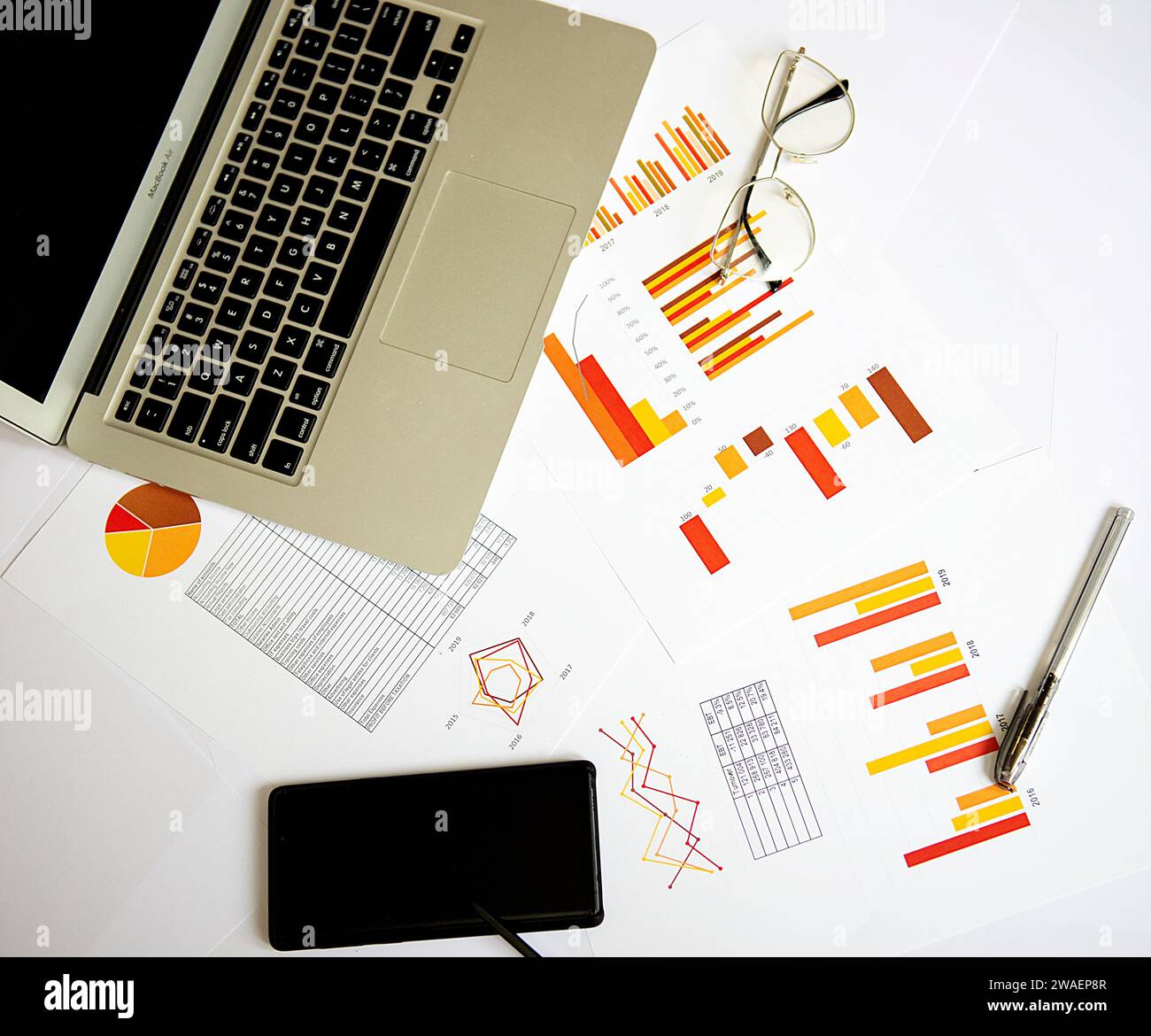 An organized workspace with a laptop computer, smartphone, eyeglasses ...