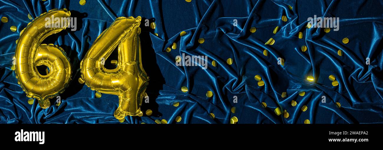 Gold foil balloon number number 64 on a background of blue velvet ...
