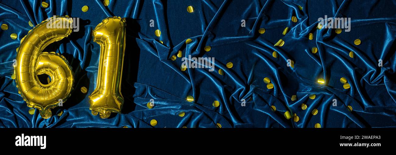 Gold foil balloon number number 61 on a background of blue velvet ...