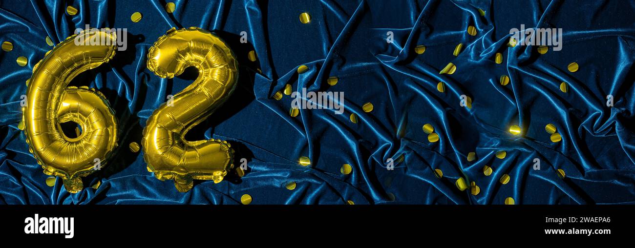 Gold foil balloon number number 62 on a background of blue velvet ...