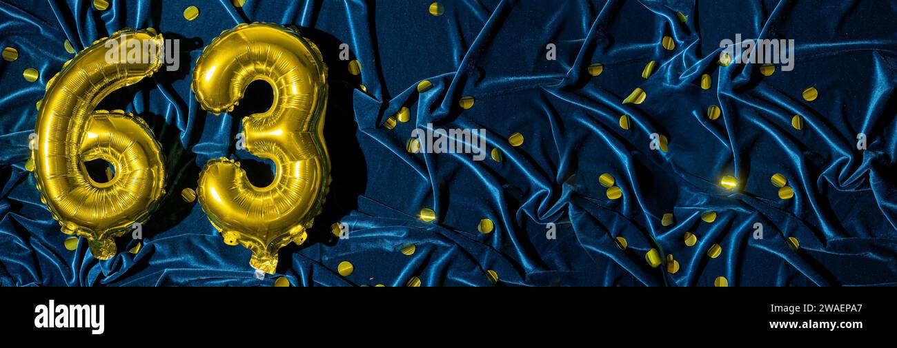 Gold foil balloon number number 63 on a background of blue velvet ...