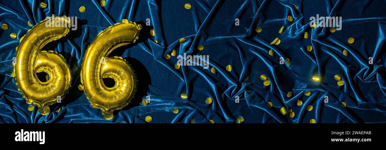 Gold foil balloon number number 66 on a background of blue velvet ...