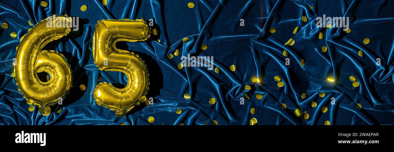 Gold foil balloon number number 65 on a background of blue velvet ...