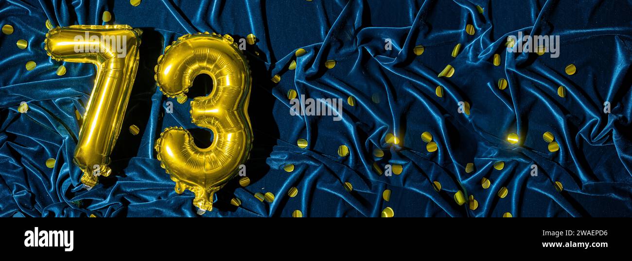 Gold foil balloon number number 73 on a background of blue velvet ...