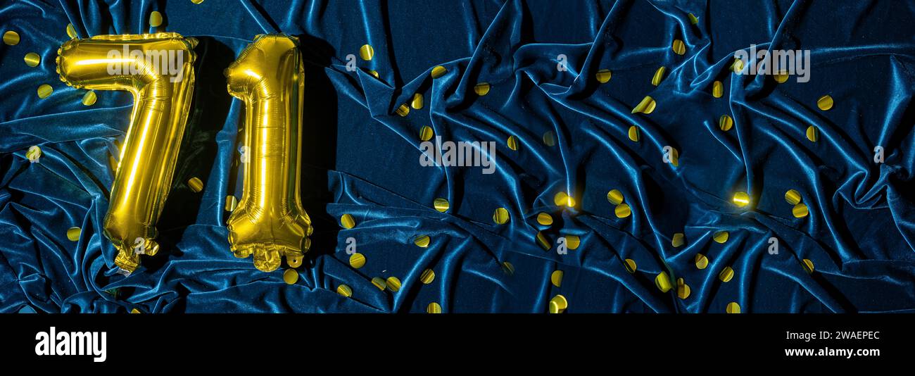 Gold foil balloon number number 71 on a background of blue velvet ...