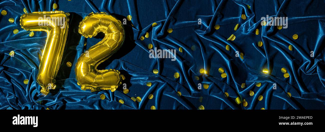 Gold foil balloon number number 72 on a background of blue velvet ...