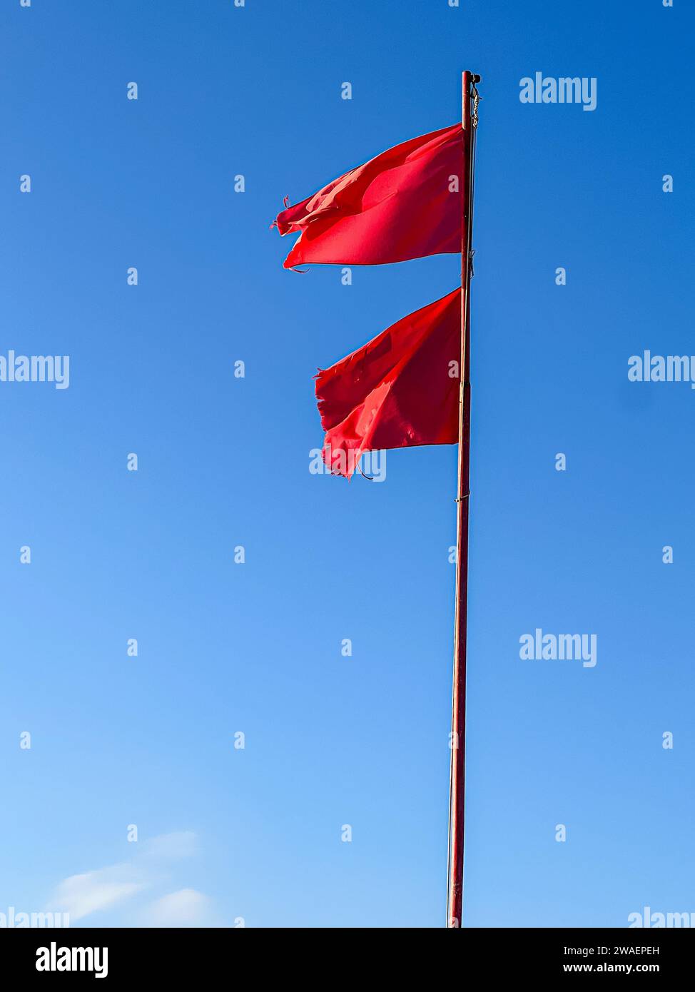 Two signal red flags raised on the beach to warn of a storm at sea ...
