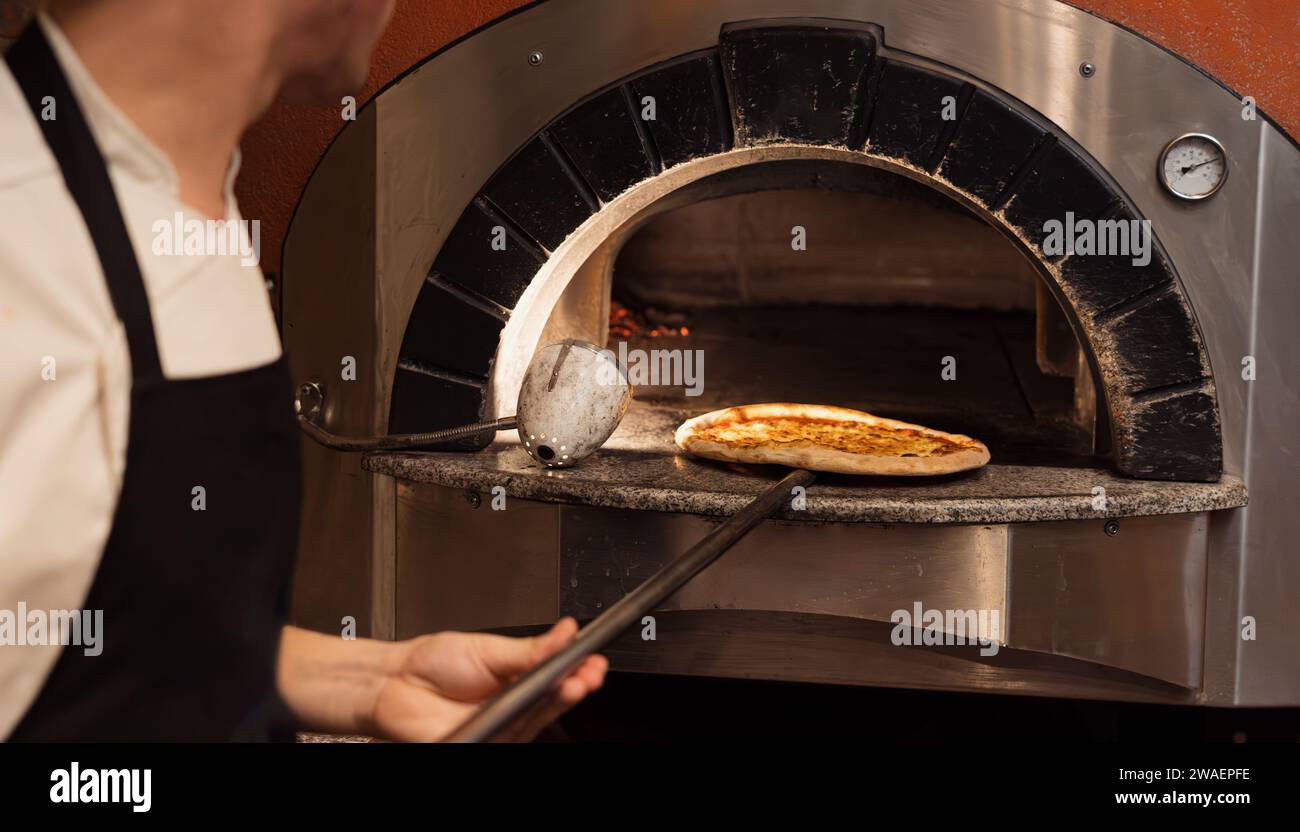 Chef Sliding Pizza Into a Modern Wood-Fired Oven Stock Photo - Alamy