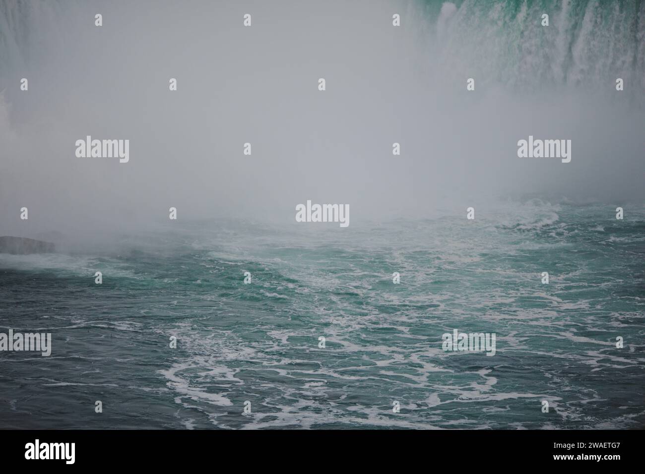 The waterfall cascades into a pool of blue water below. Niagara Falls ...