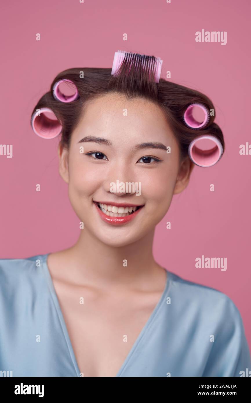 Beautiful girl in hair curlers on pink background Stock Photo - Alamy