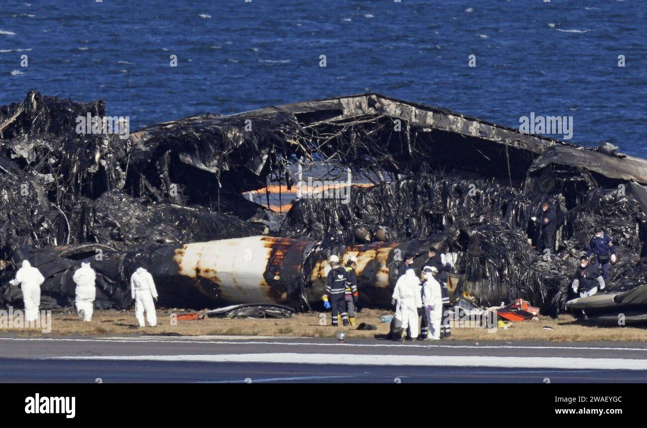 Officials investigate the wreckage of Japan Airlines plane at Haneda ...