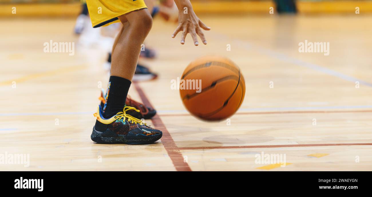 Horizontal image of young basketball player bouncing ball in training ...