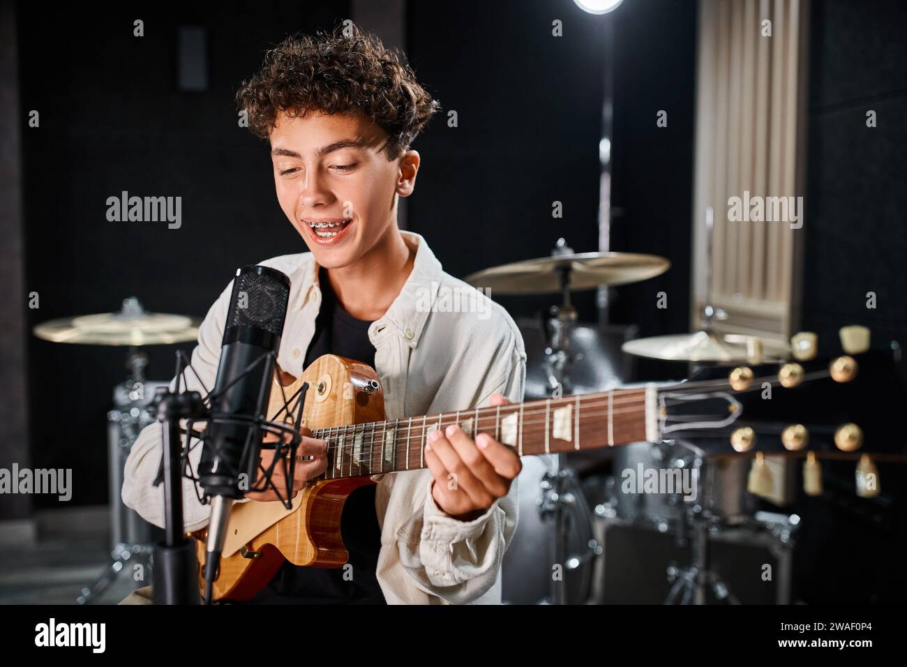talented cute teenage boy in casual attire playing guitar and singing ...