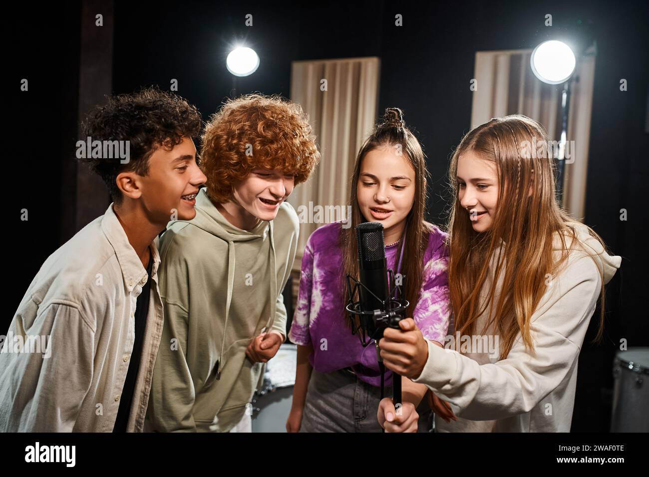 four joyous talented teenagers in casual outfits singing together while ...