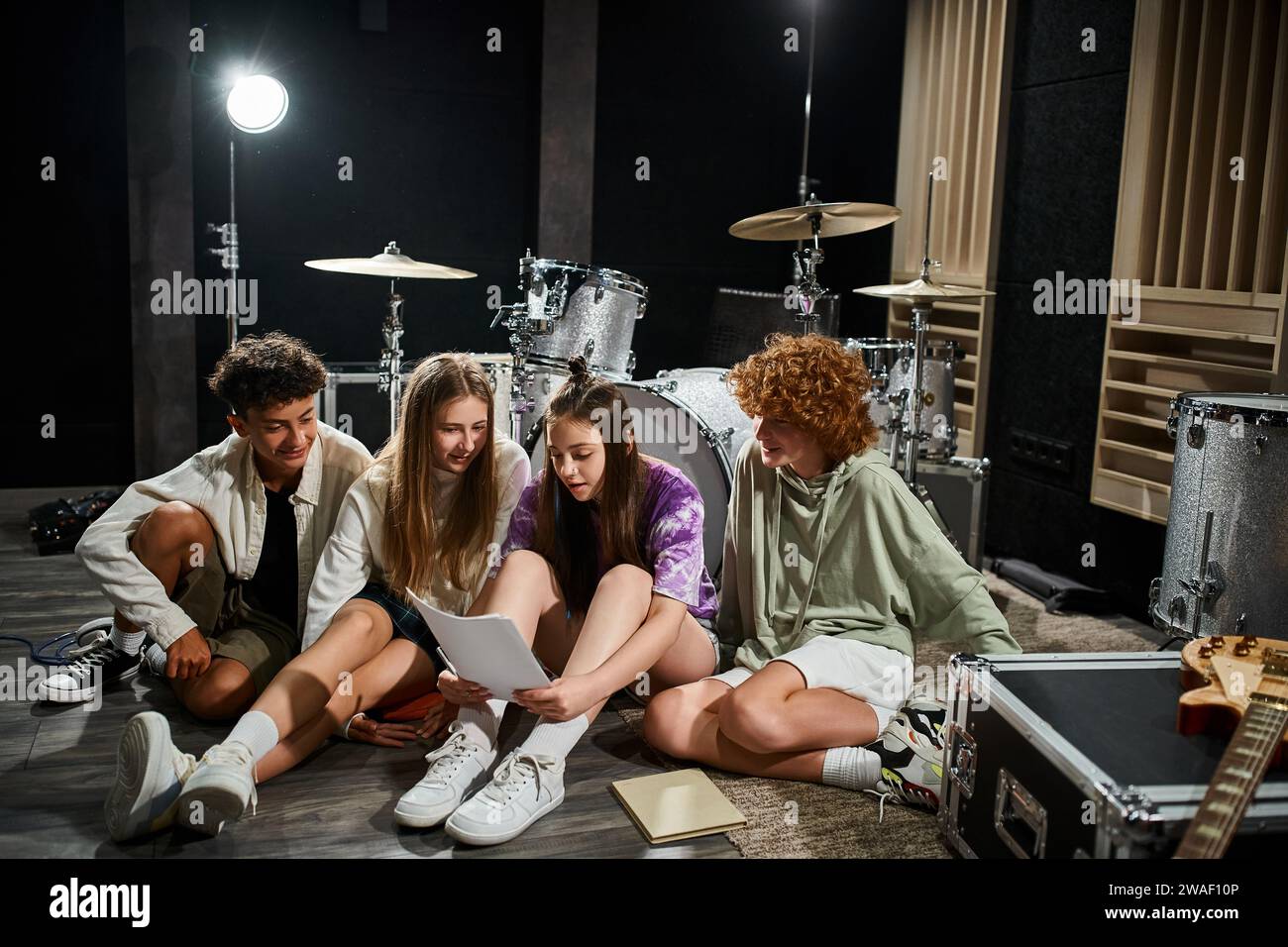 adorable teenagers in everyday attires sitting in studio and looking at ...