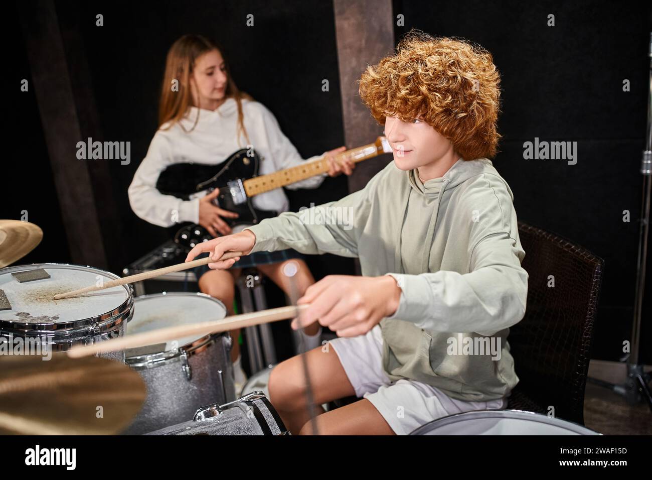 focus on concentrated cute teenage boy playing drums next to his ...