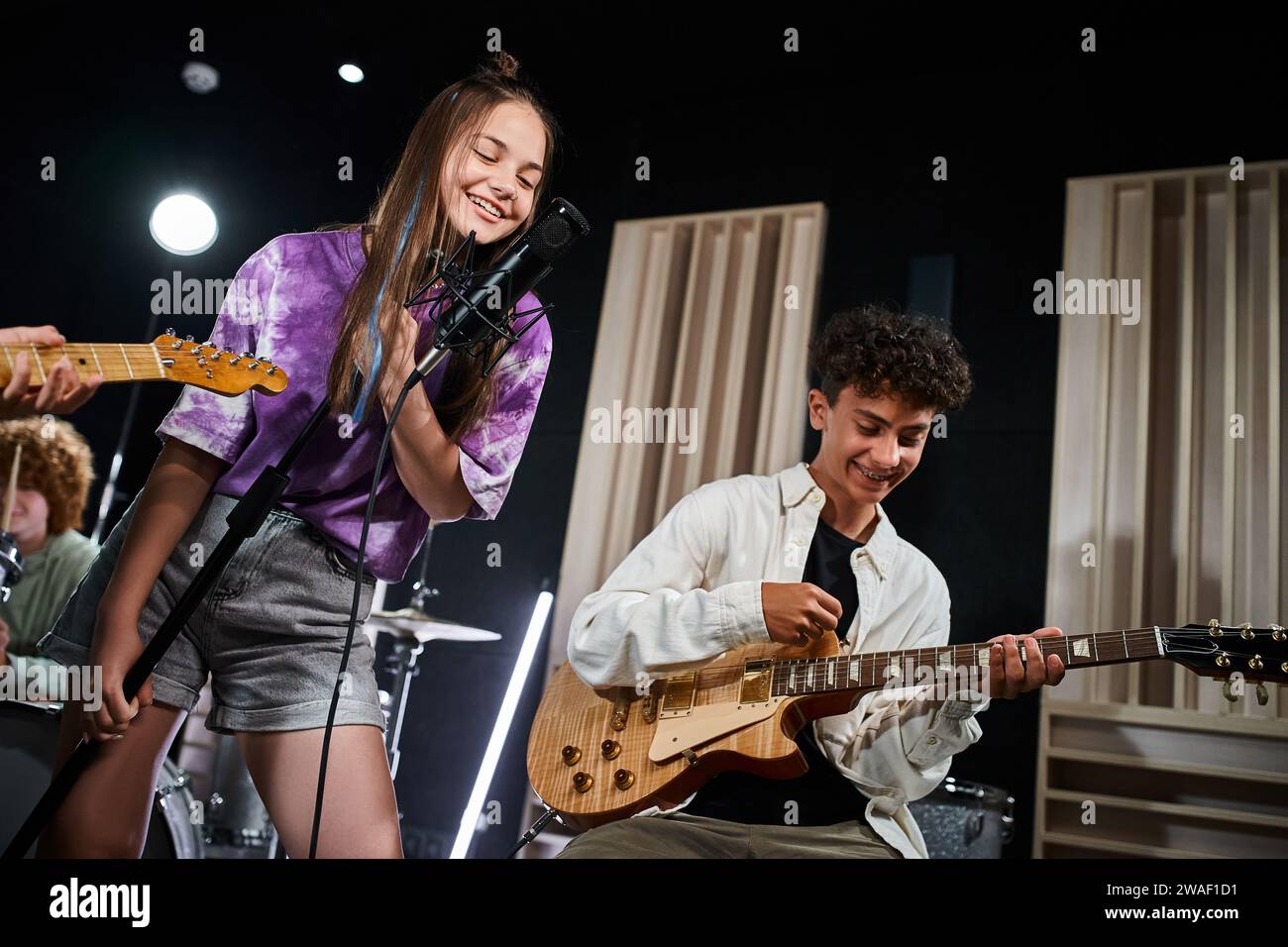 adorable joyful teenage girl singing happily while her friend playing ...