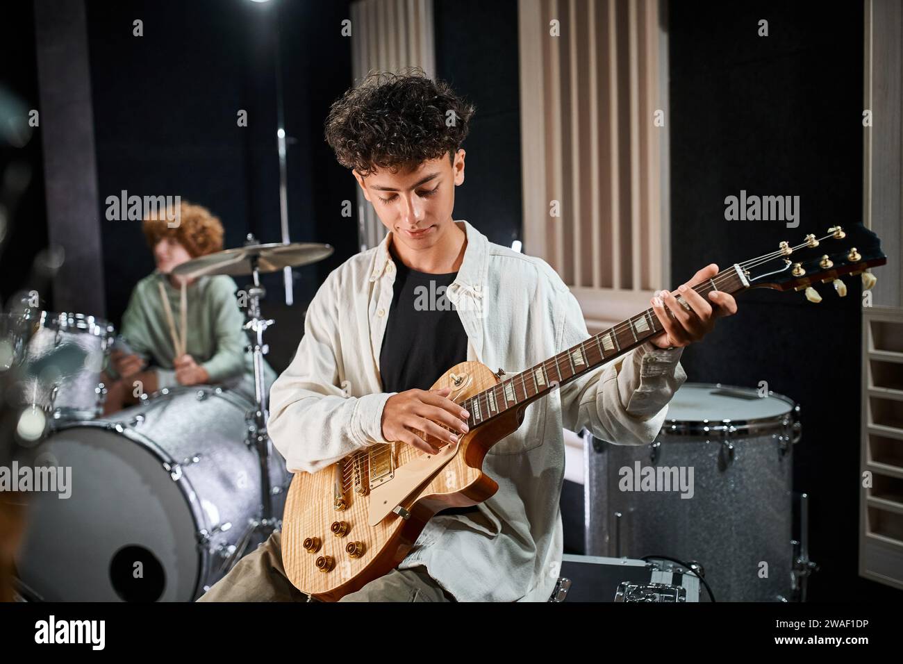 focus on cute talented teenage boy playing guitar with his blurred ...