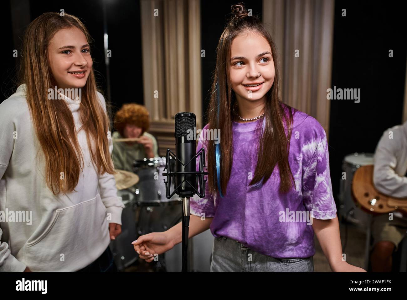 pretty jolly teens in casual attires singing and playing instruments in ...