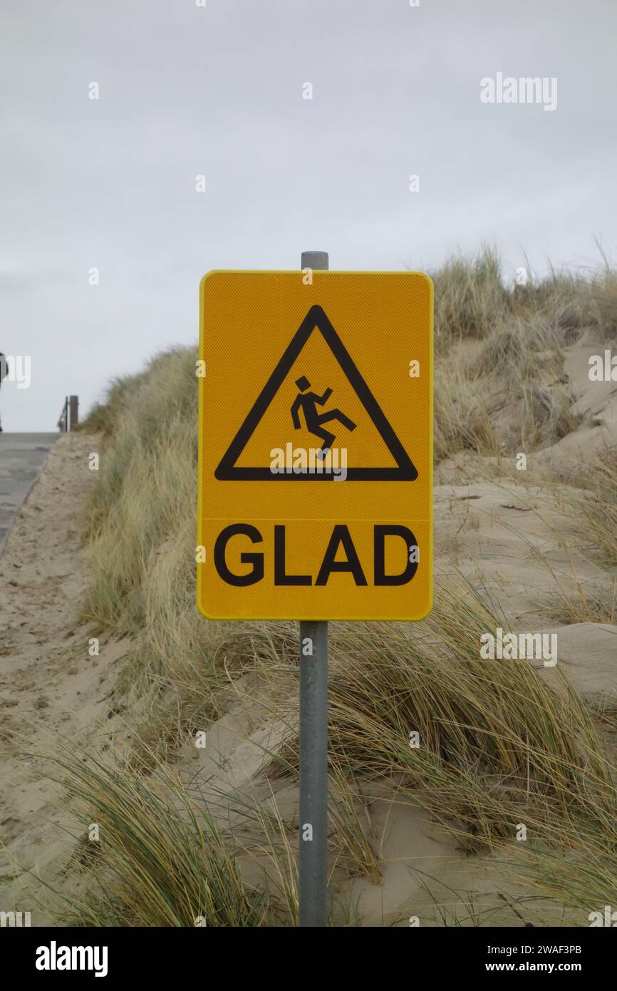 A yellow caution sign with the word Glad written on it on the beach ...