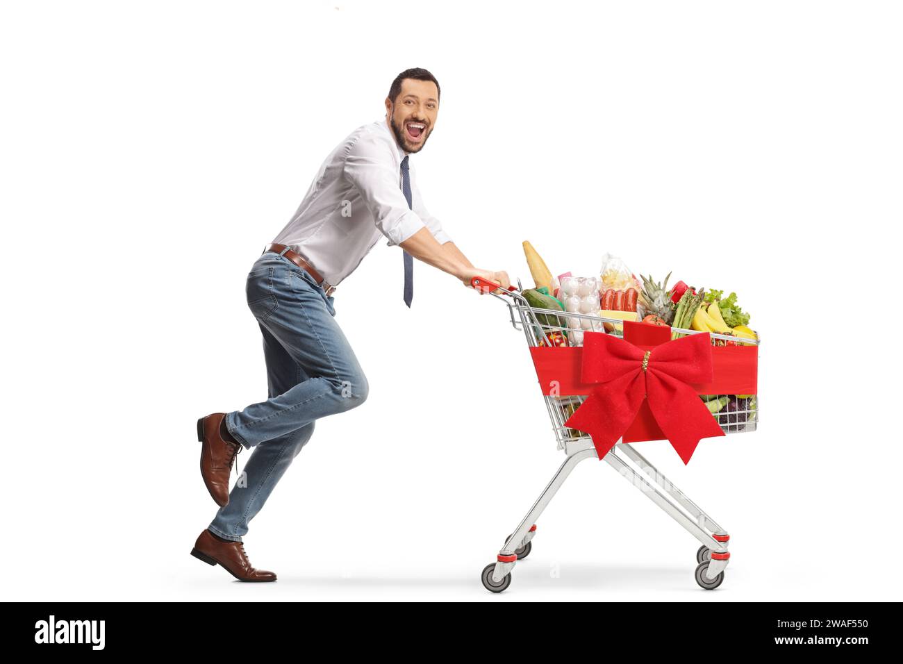 Excited man running with a shopping cart tied with a bow and smiling at ...