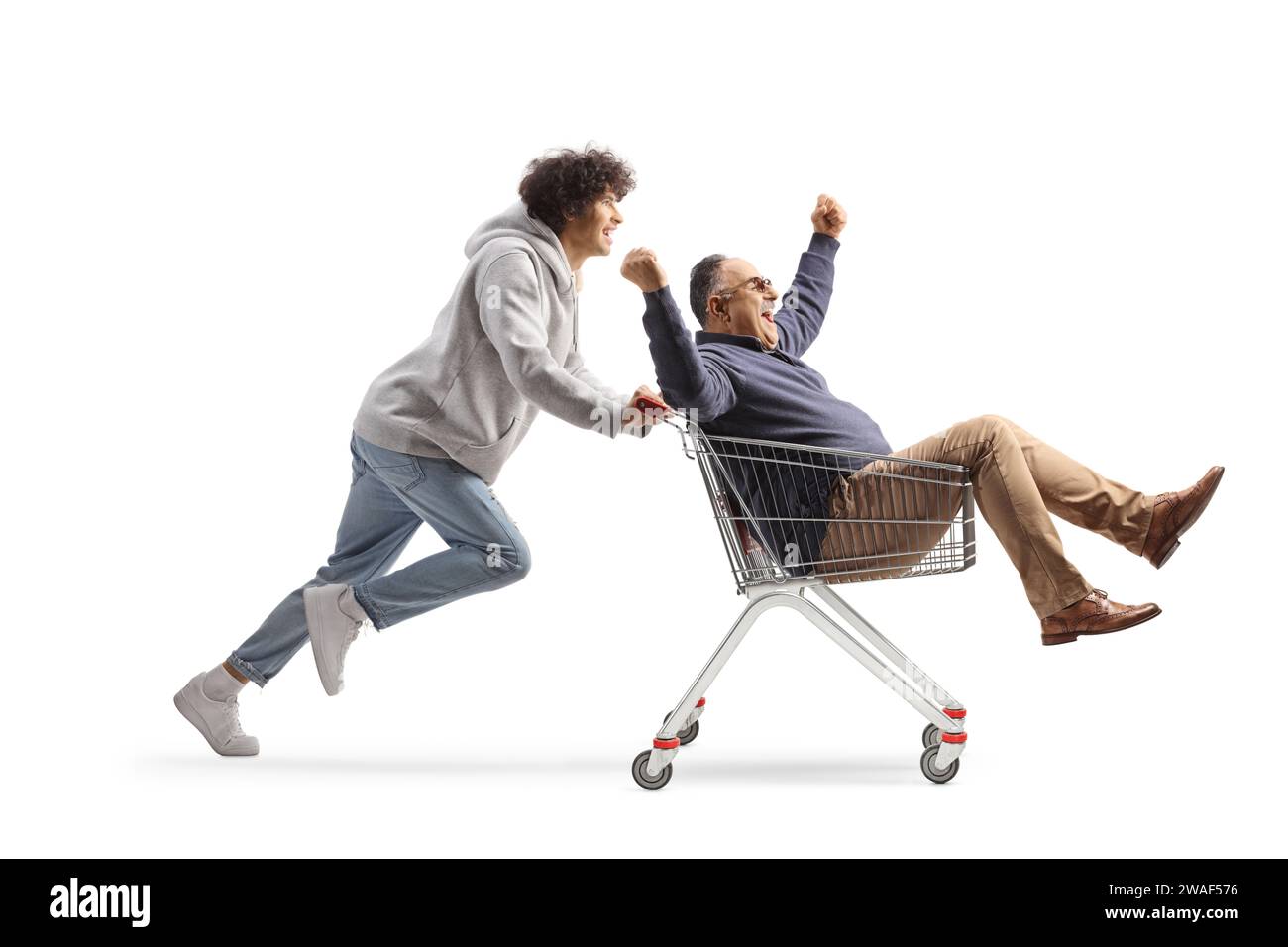 Young man running and pushing a happy mature man inside a shopping cart ...