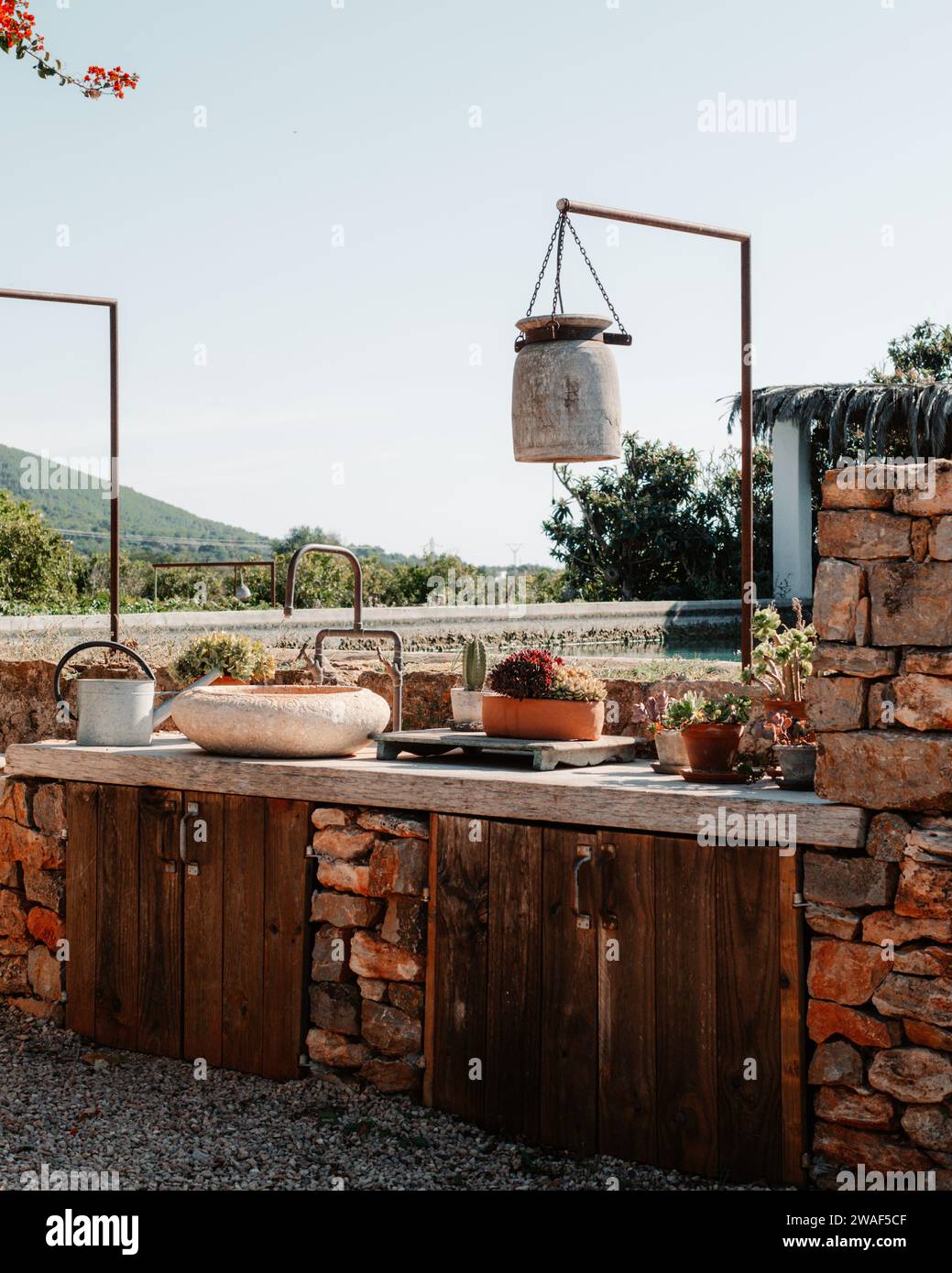 An exterior kitchen countertop with a suspended cooking pot in a rural ...